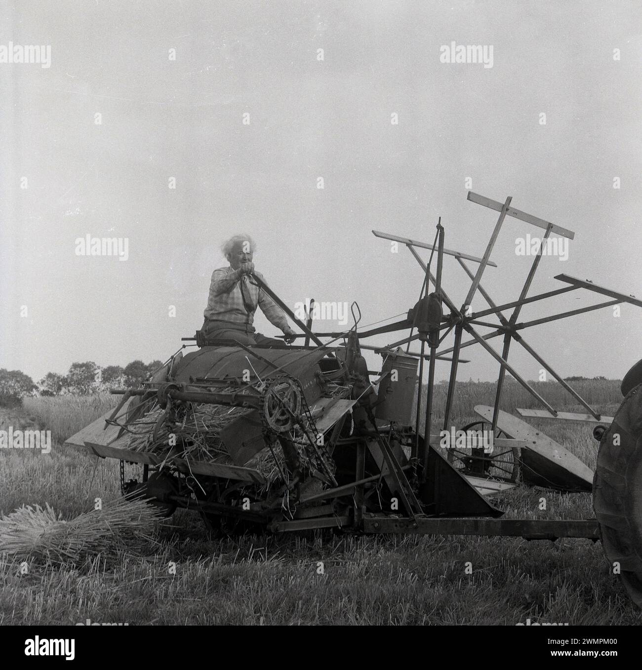 1960s, historical, harvest time, outside in a field, a farmer sitting ...