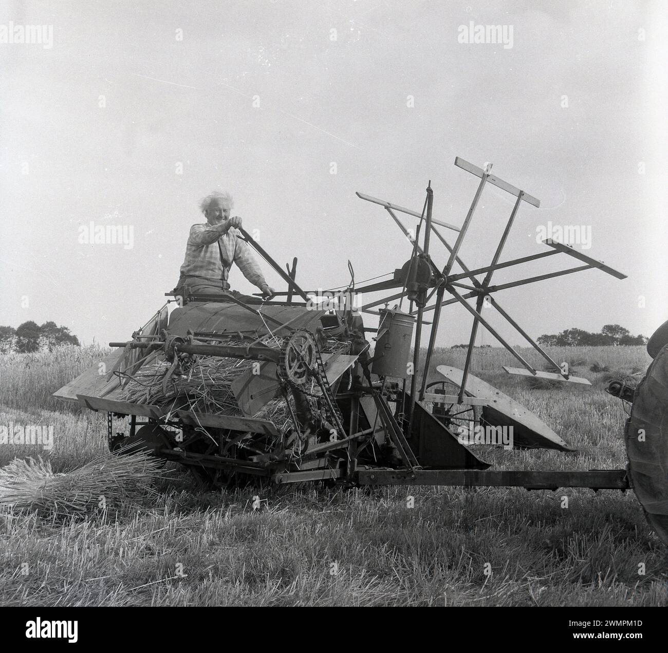 1960s, historical, harvest time, outside in a field, a farmer sitting ...