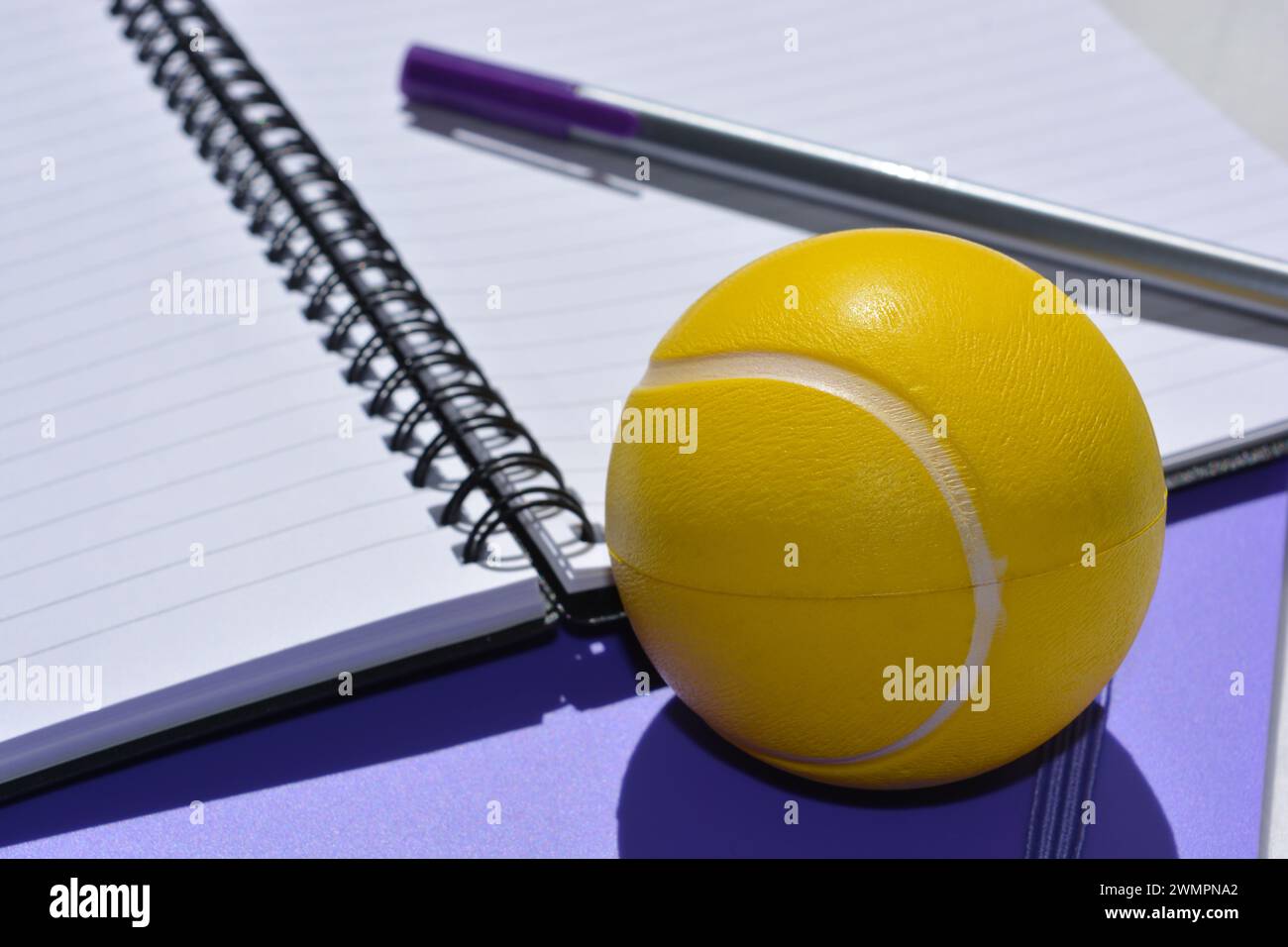 Yellow stress ball and pen on an empty spiral bound notebook Stock ...