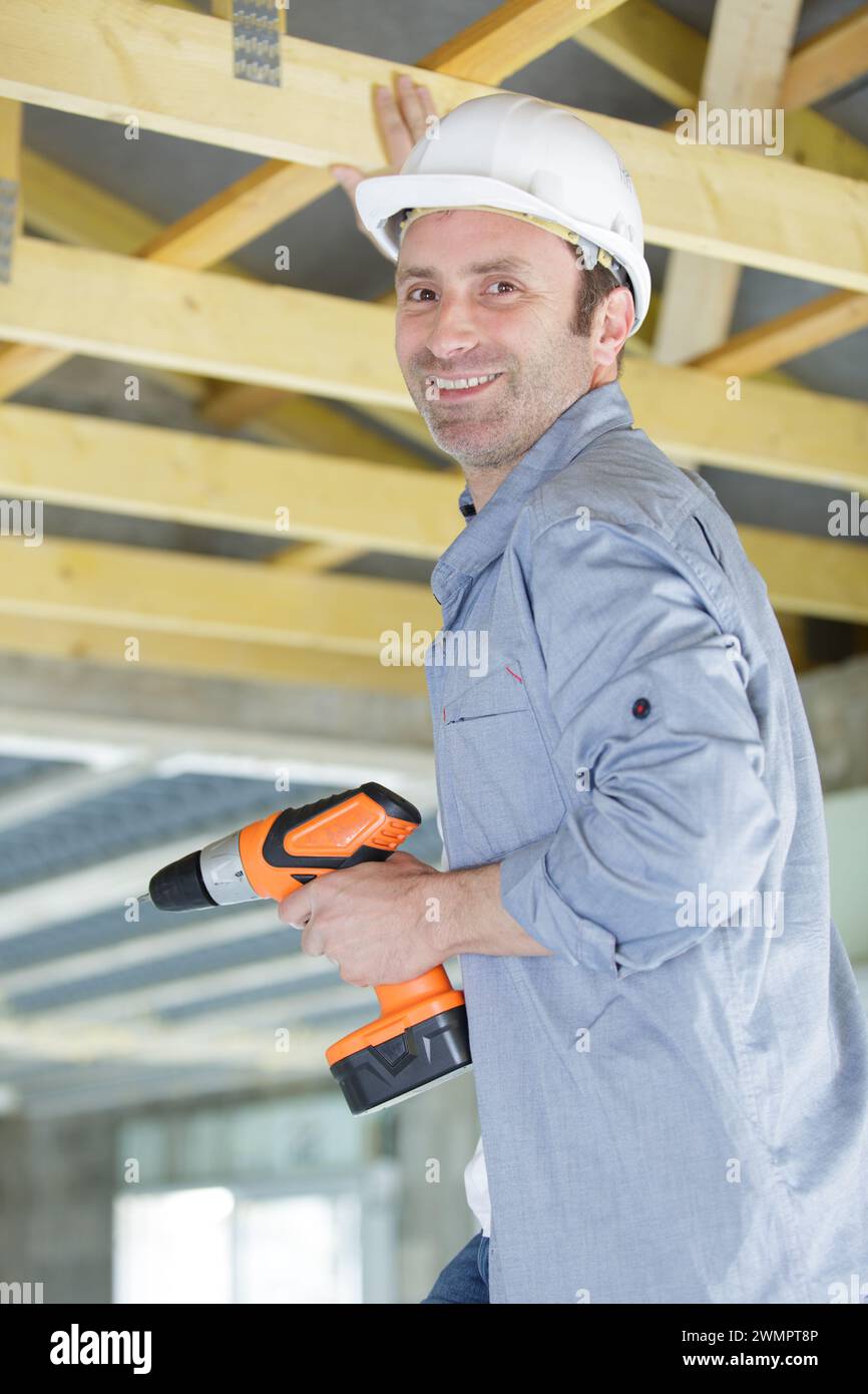 builder holding power tool to work on roof beam Stock Photo - Alamy