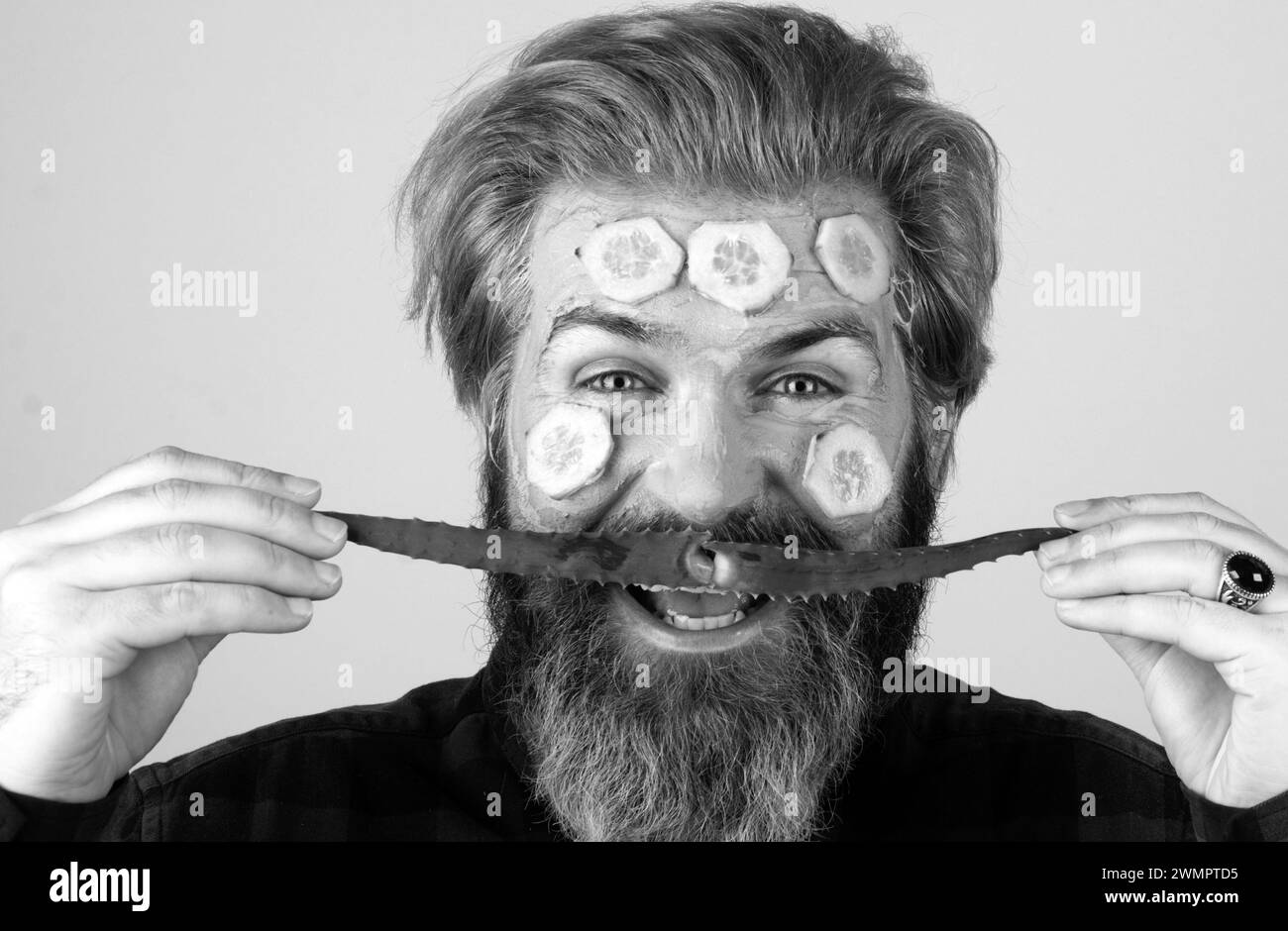 Funny male model with clay mask and cucumber slices, aloe vera ...