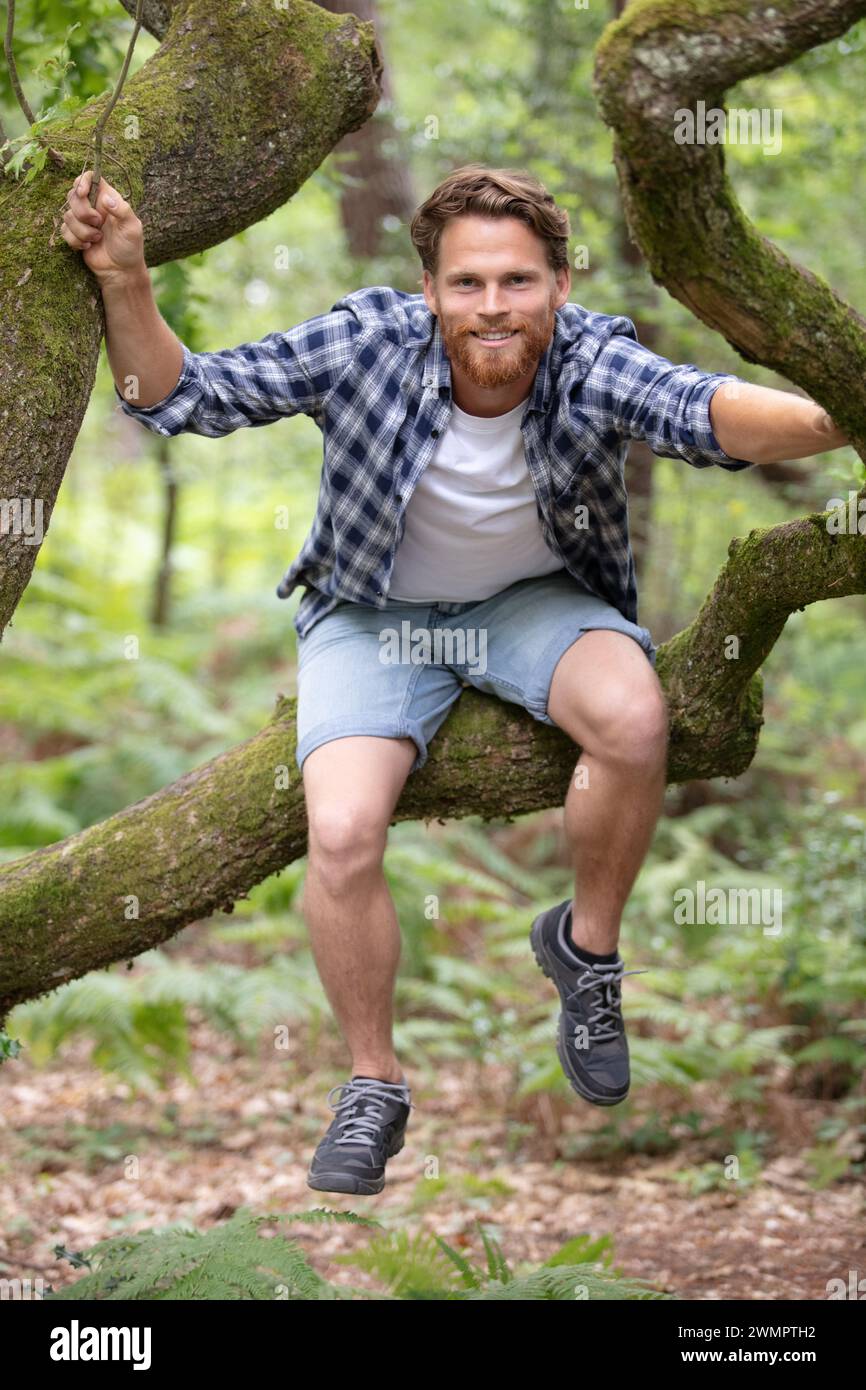 man sitting on a suspended tree branch Stock Photo - Alamy