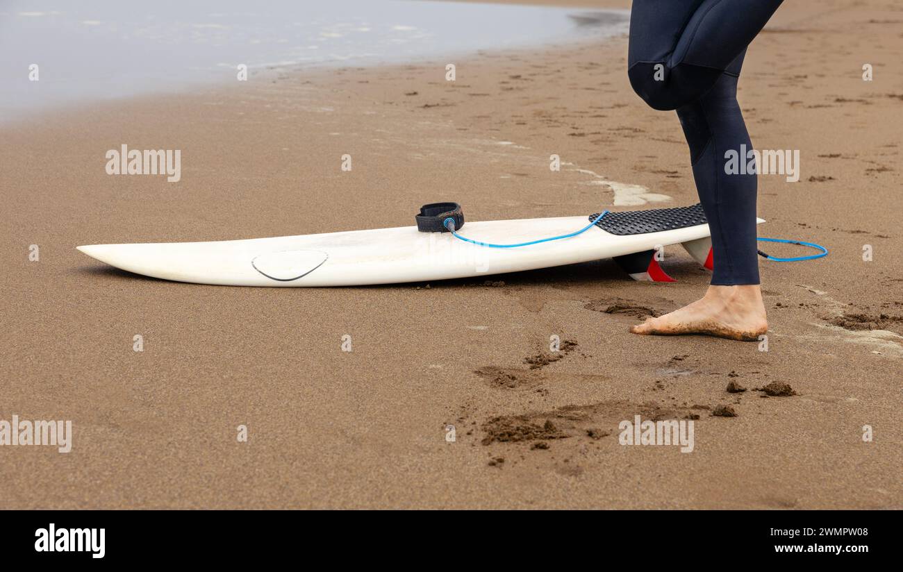 Cut out of a surfer's legs on the beach with a surfboard Stock Photo ...