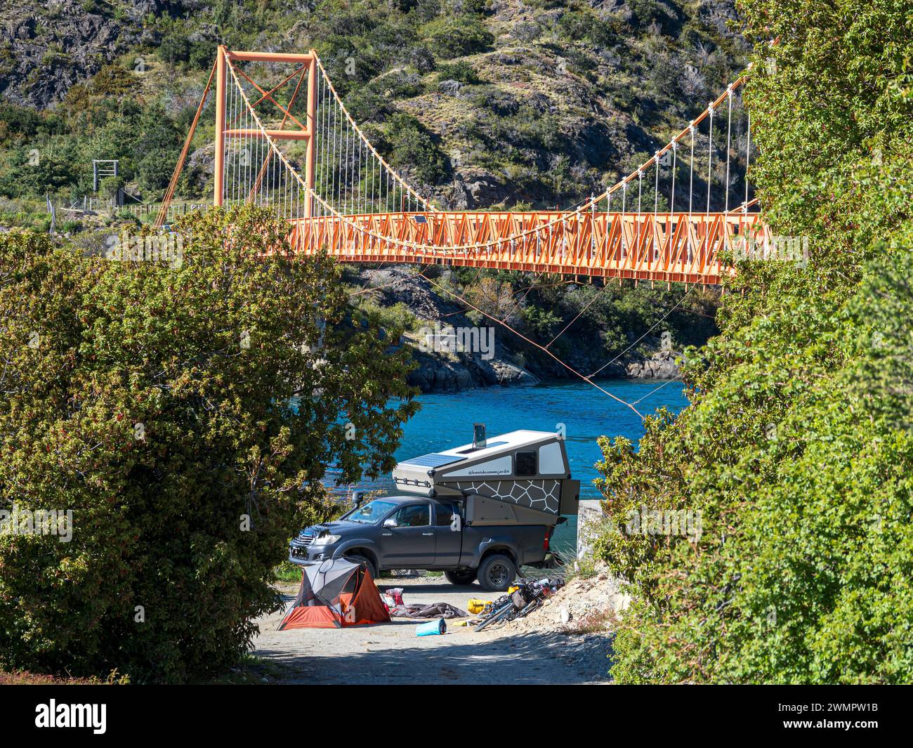 4x4 camper and cyclists staying overnight in a tent, below suspension ...