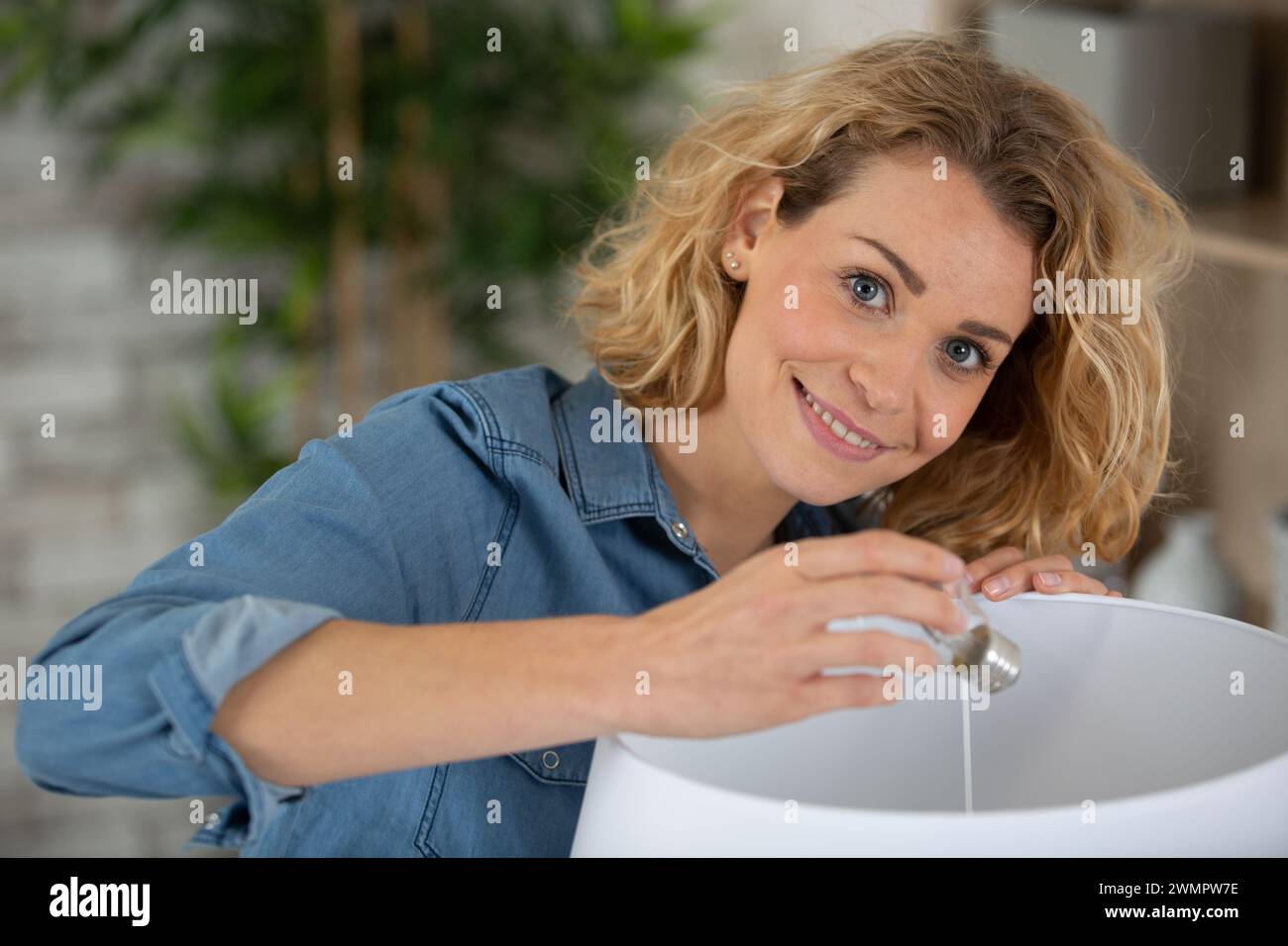 happy woman is fixing broken lamp Stock Photo - Alamy