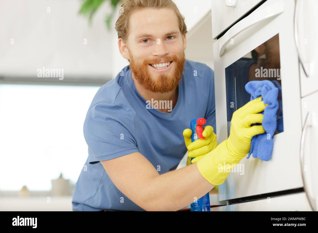 happy young man in overall cleaning oven Stock Photo - Alamy