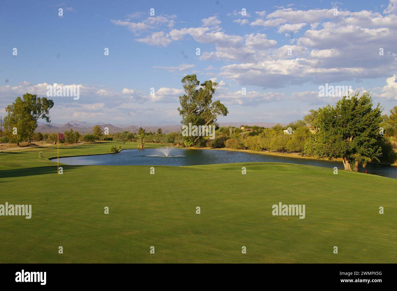 A scenic view from hilltop of golf course, mountains, and clear blue ...