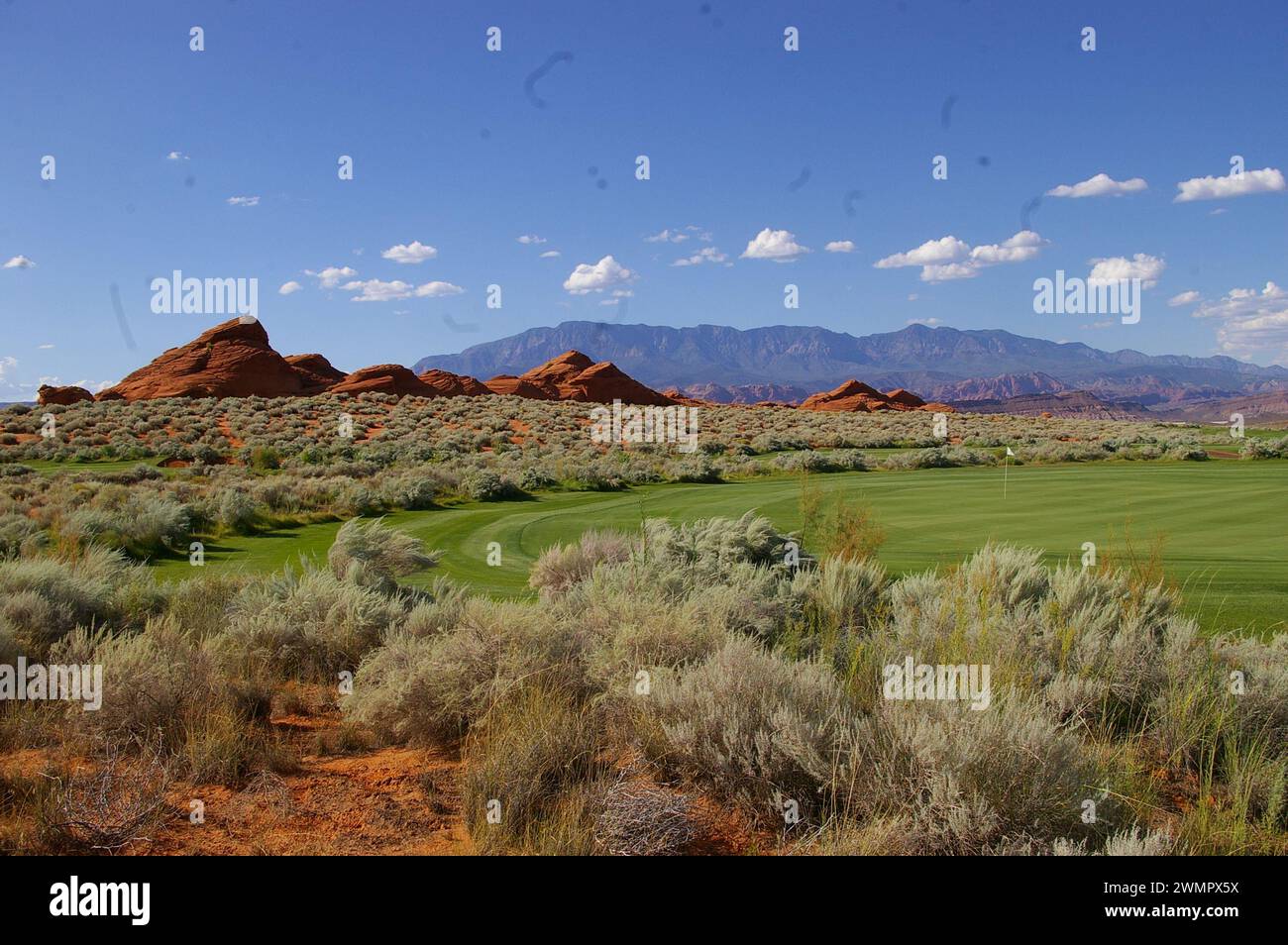 A scenic view from hilltop of golf course, mountains, and clear blue ...