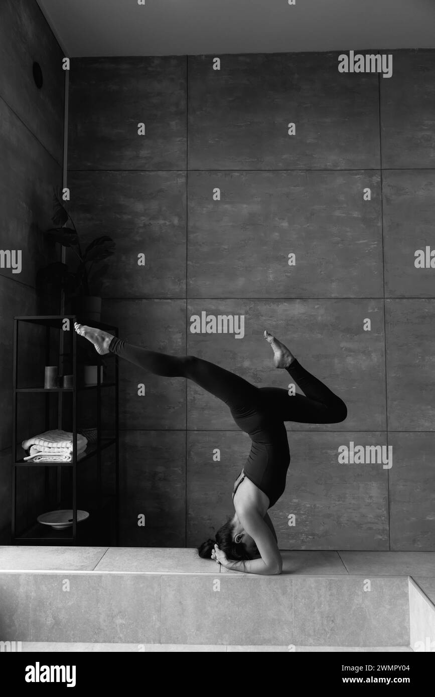 Young sporty attractive woman practicing yoga doing headstand exercise ...