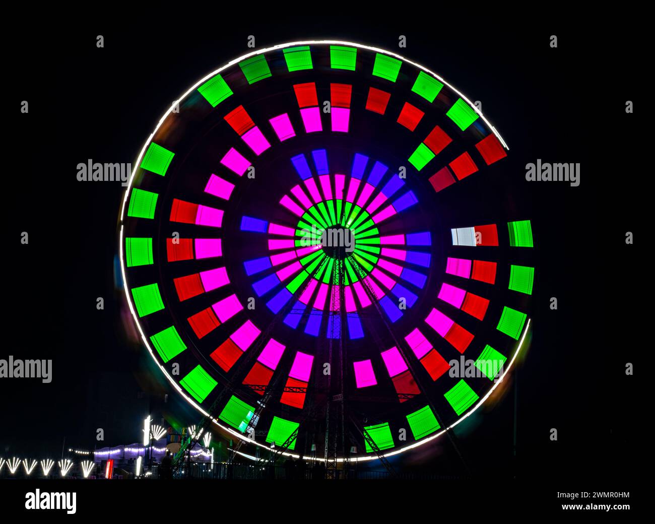 Intentional camera movement, slow shutter blur image of giant Ferris wheel illuminated and ...