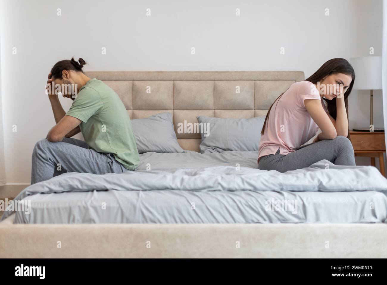 Upset couple sitting apart on bed, facing away Stock Photo - Alamy