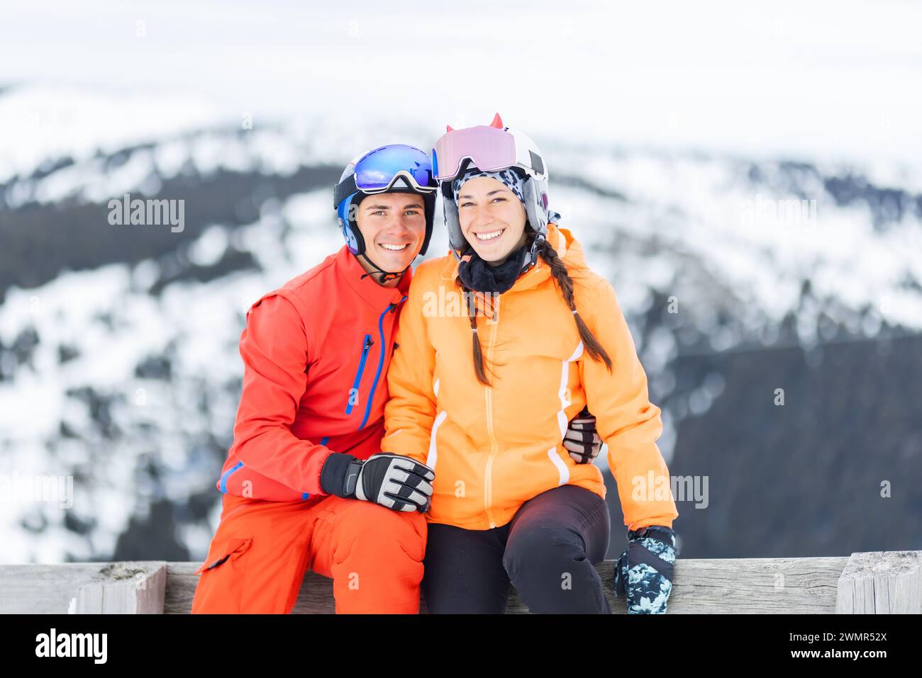 Ski friends having fun on a wooden fence. Couple in love posing ...