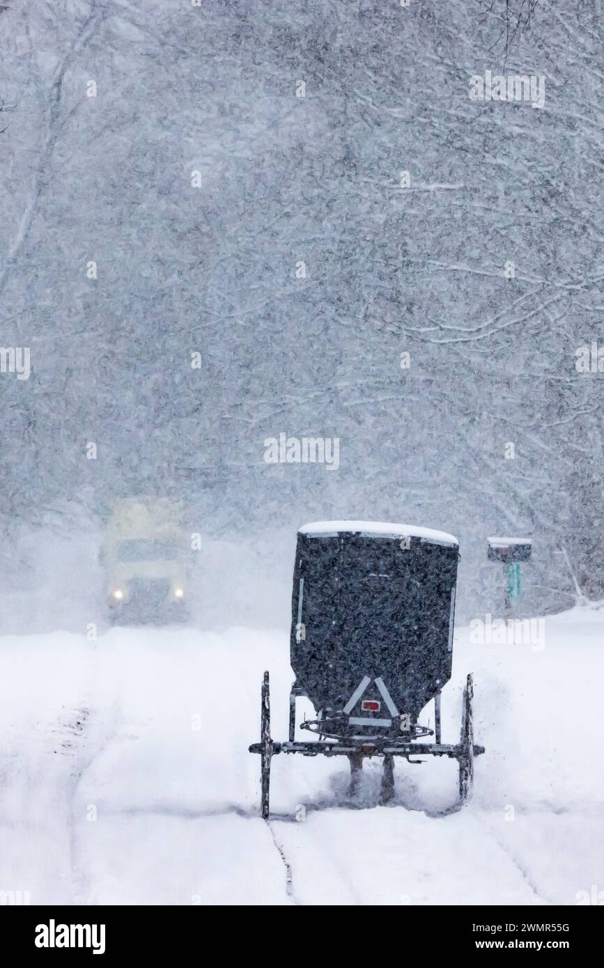 Amish buggy and delivery truck on country road during a snowstorm in ...
