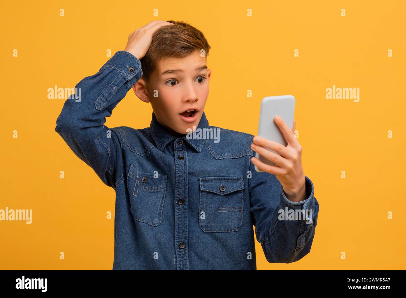Surprised teen boy staring at smartphone screen and opening mouth in ...