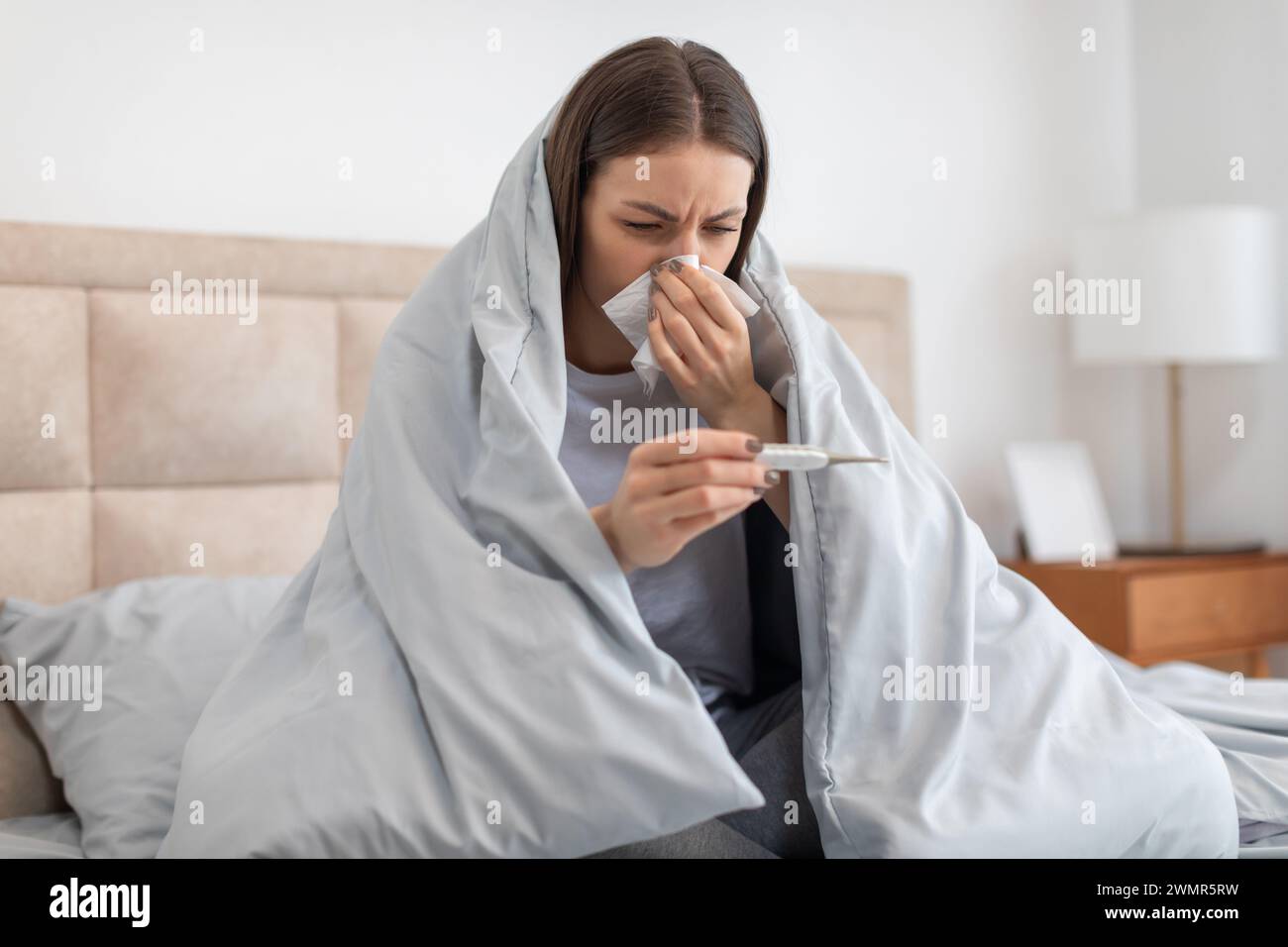 Sick woman in bed, checking temperature with thermometer, feeling ...