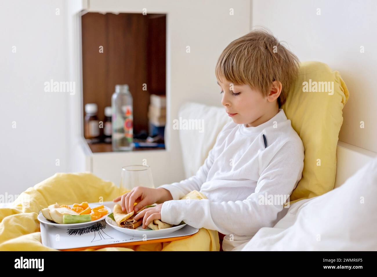 Sick child, toddler boy lying in bed with a fever, having breakfast ...