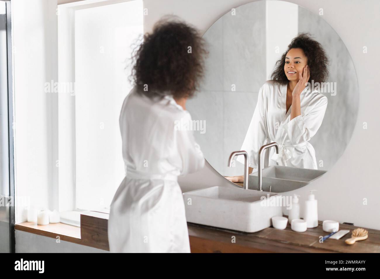 Beautiful black lady with perfect skin complexion touches face indoor ...