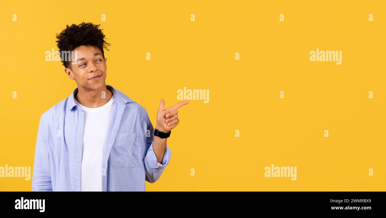 Confident black guy pointing sideways on yellow background Stock Photo ...