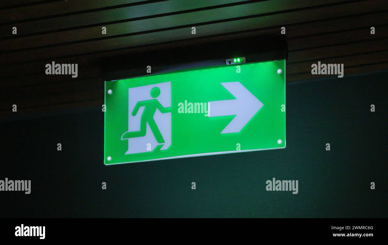 A green exit sign glowing in the darkness, indicating a way out with a ...