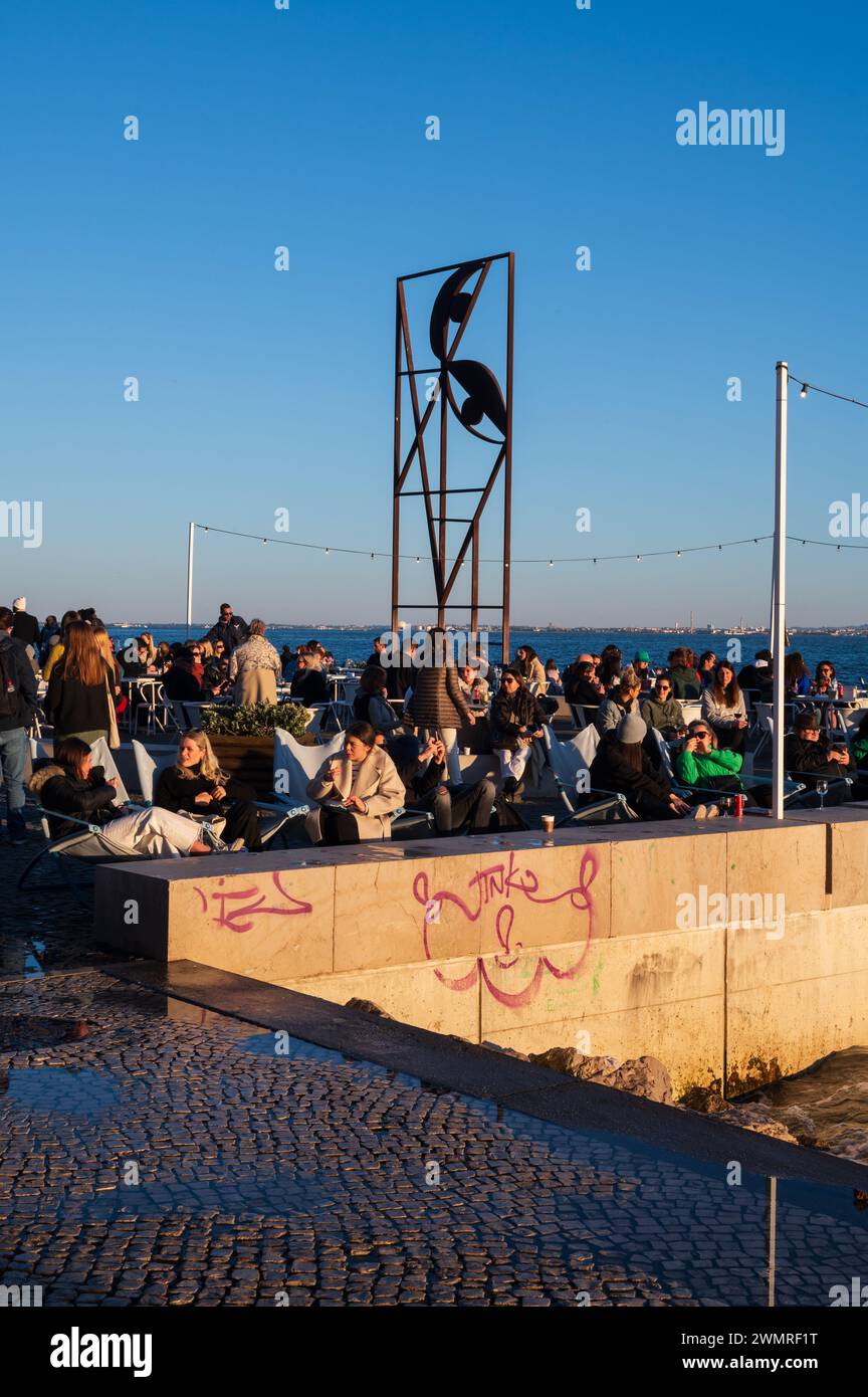 People enjoying the sunset on Ribeira das Naus, the riverfront ...