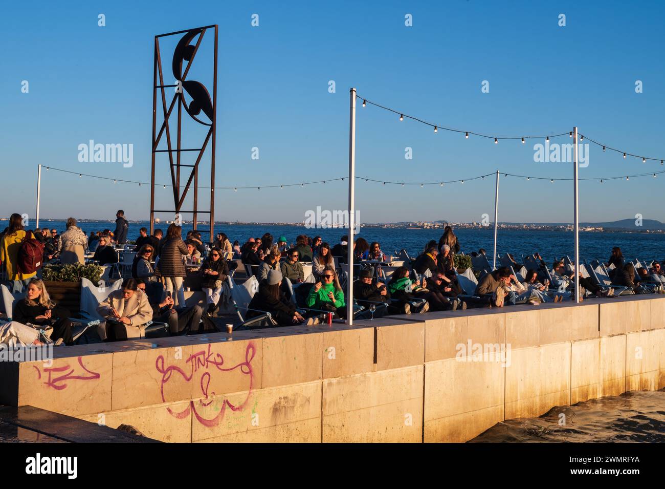 People enjoying the sunset on Ribeira das Naus, the riverfront ...