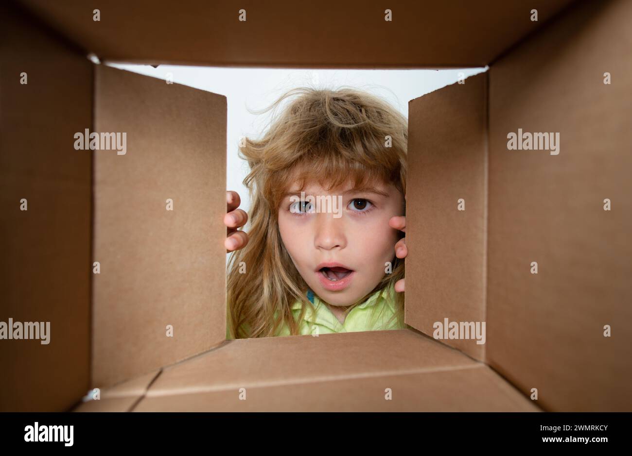 Kid boy unpacking and opening carton box looking inside with surprise ...