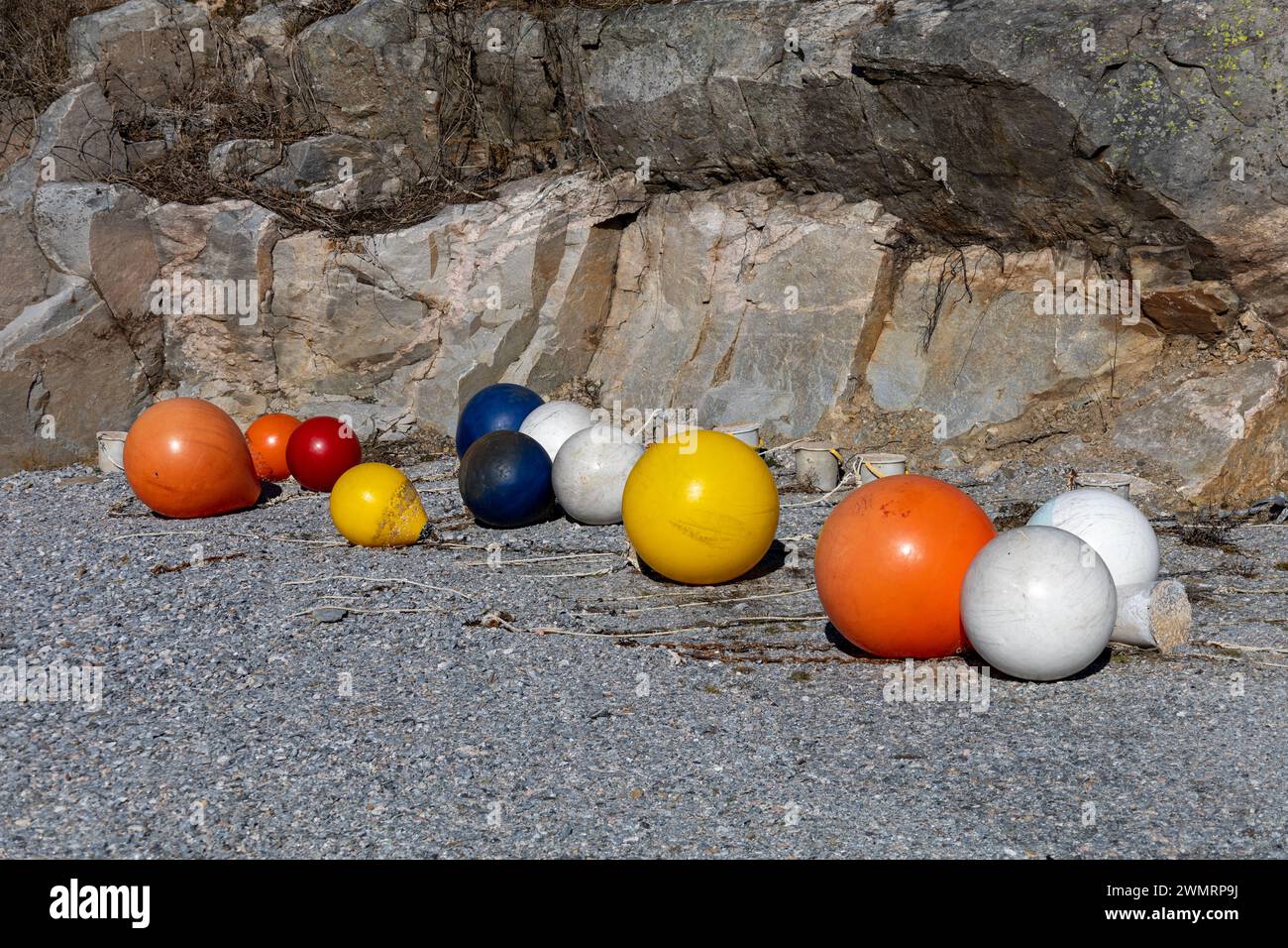 Plastic buoys laying on the shore in the sunshine. Rocks in background ...