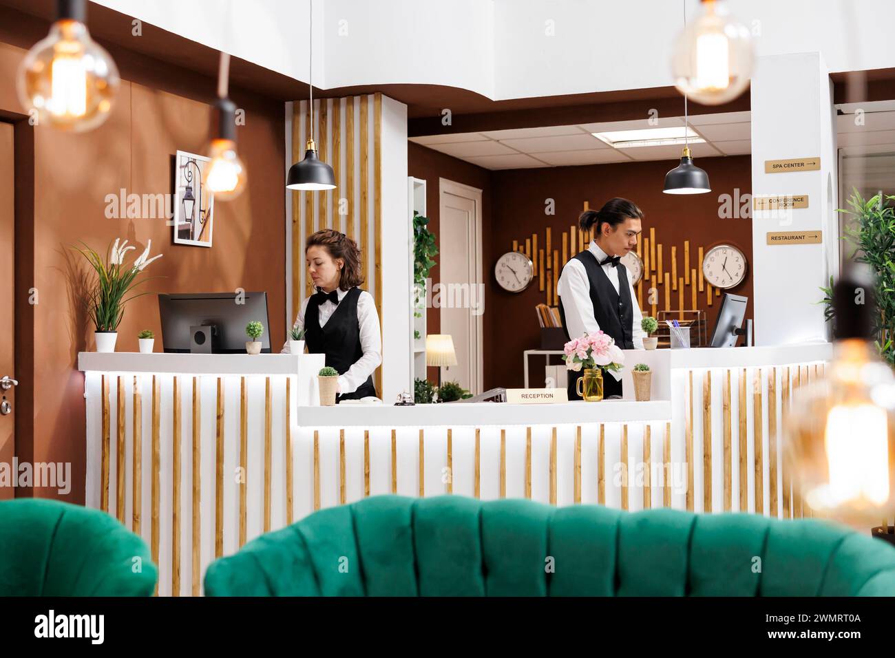 Professional employees checking reservations at front desk in hotel ...