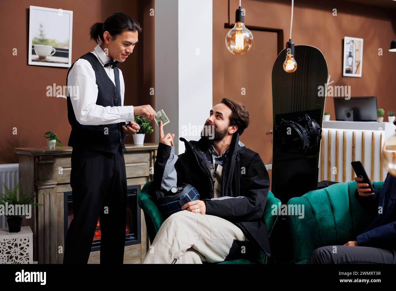 In hotel reception, friendly waiter caters to couple with skiing and ...