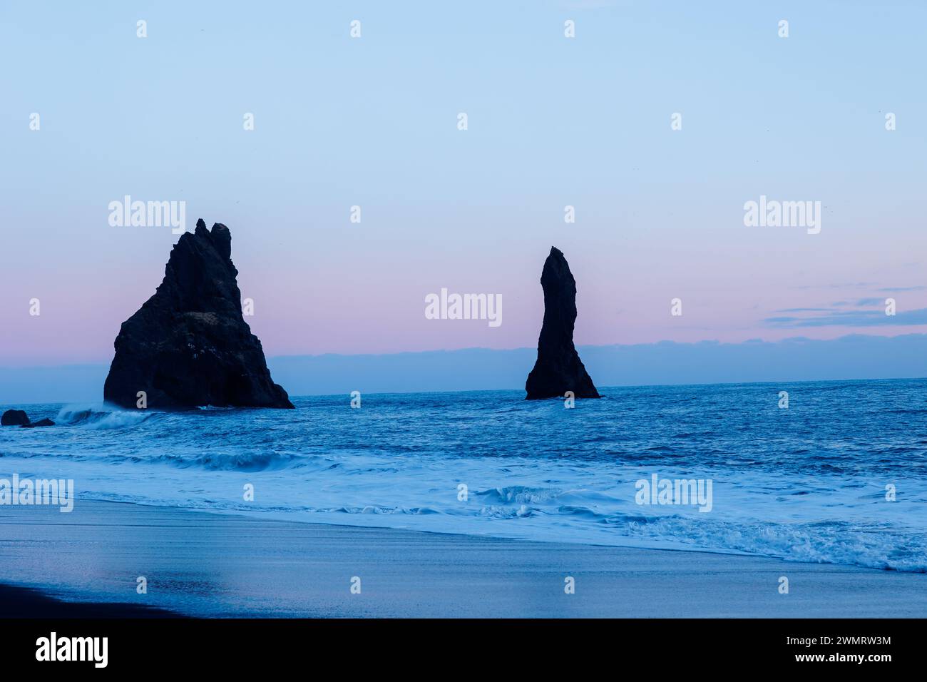 Reynisfjara black sand beach with pink sky near reynisfjall mountain ...