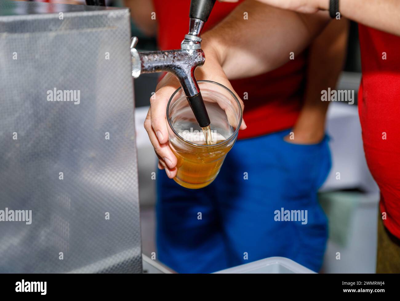 Beer flowing from a tap into a clear glass held by a person Stock Photo ...