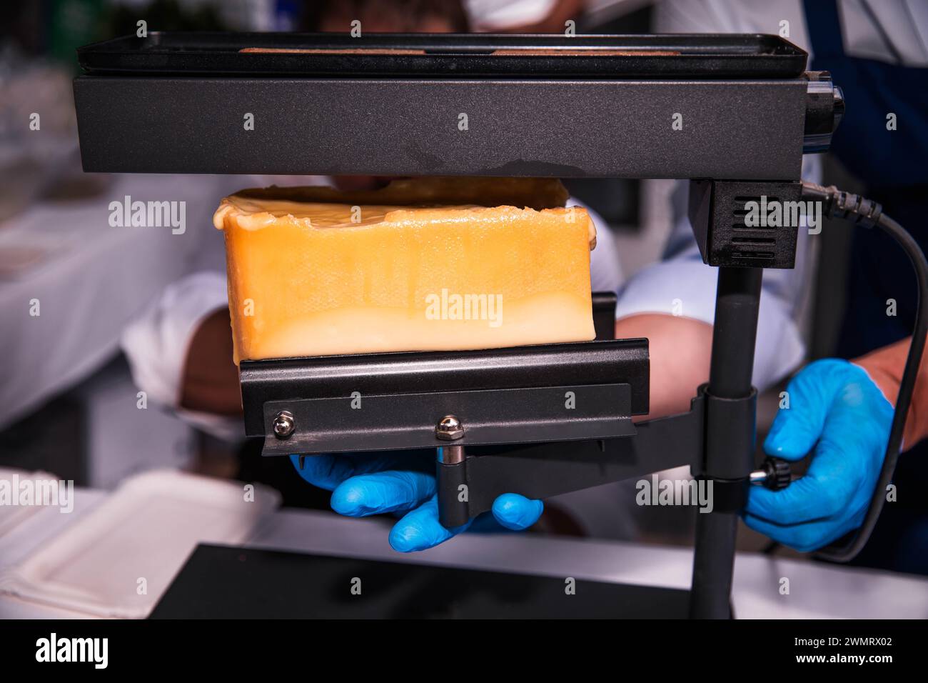 Electric Cheese Melter Slicing through a Wheel of Raclette Cheese Stock ...