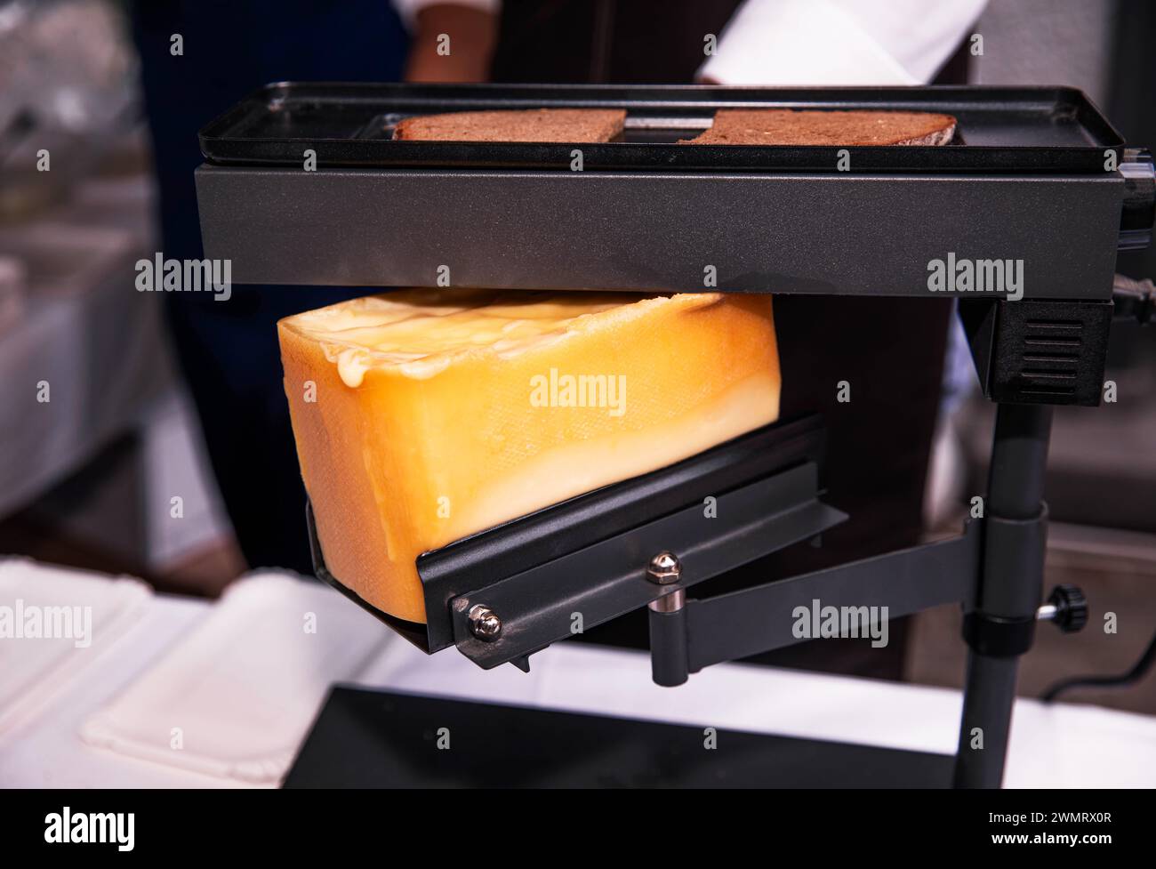 Golden raclette cheese melting on an electric griller device Stock ...