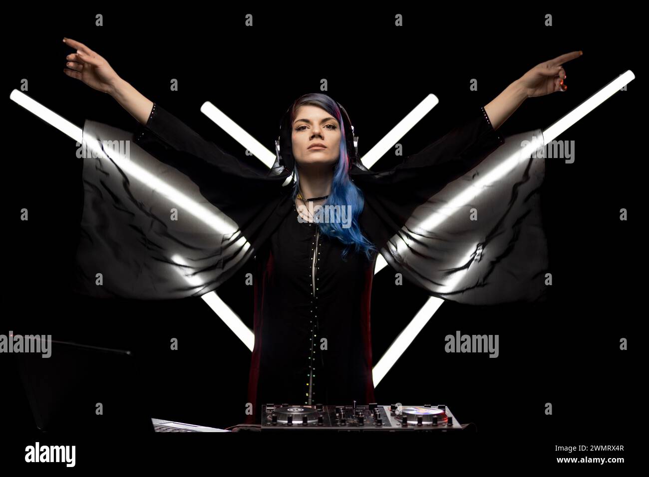 A female DJ with vibrant blue hair is actively mixing music at a ...