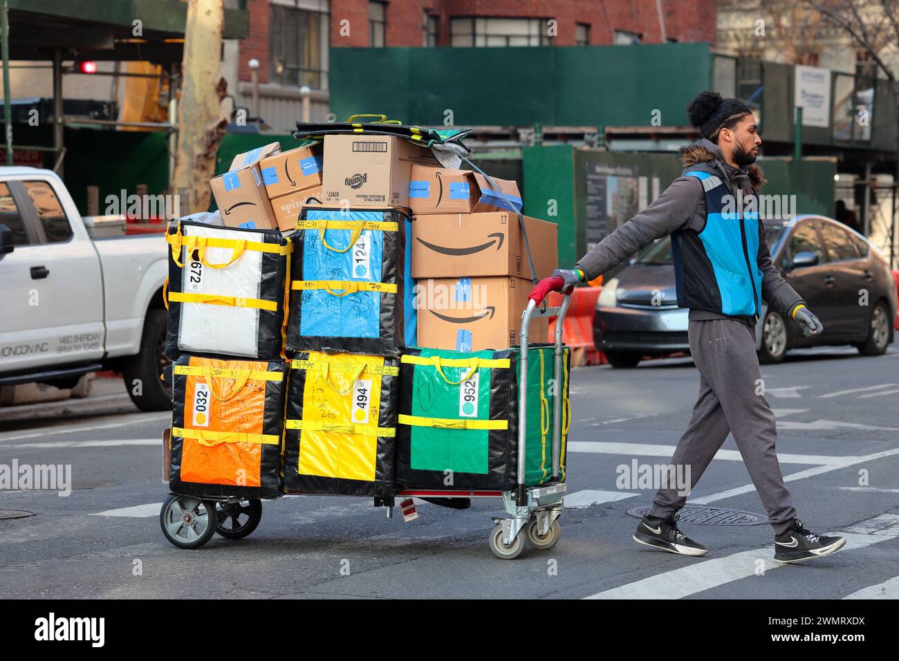 An Amazon Delivery worker with a hand truck full of packages walks ...