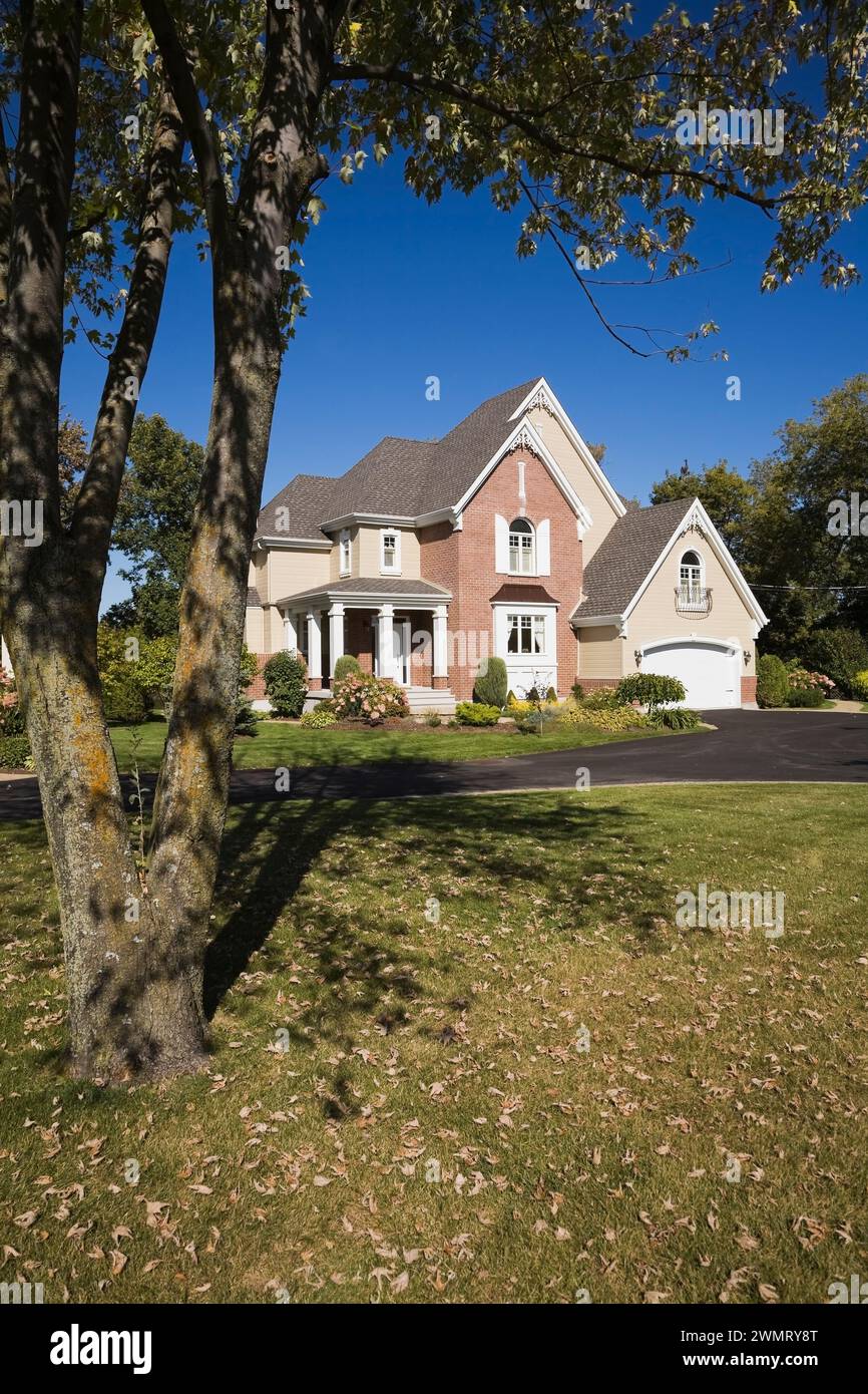 Two story red brick and tan clapboard cladded home with landscaped ...