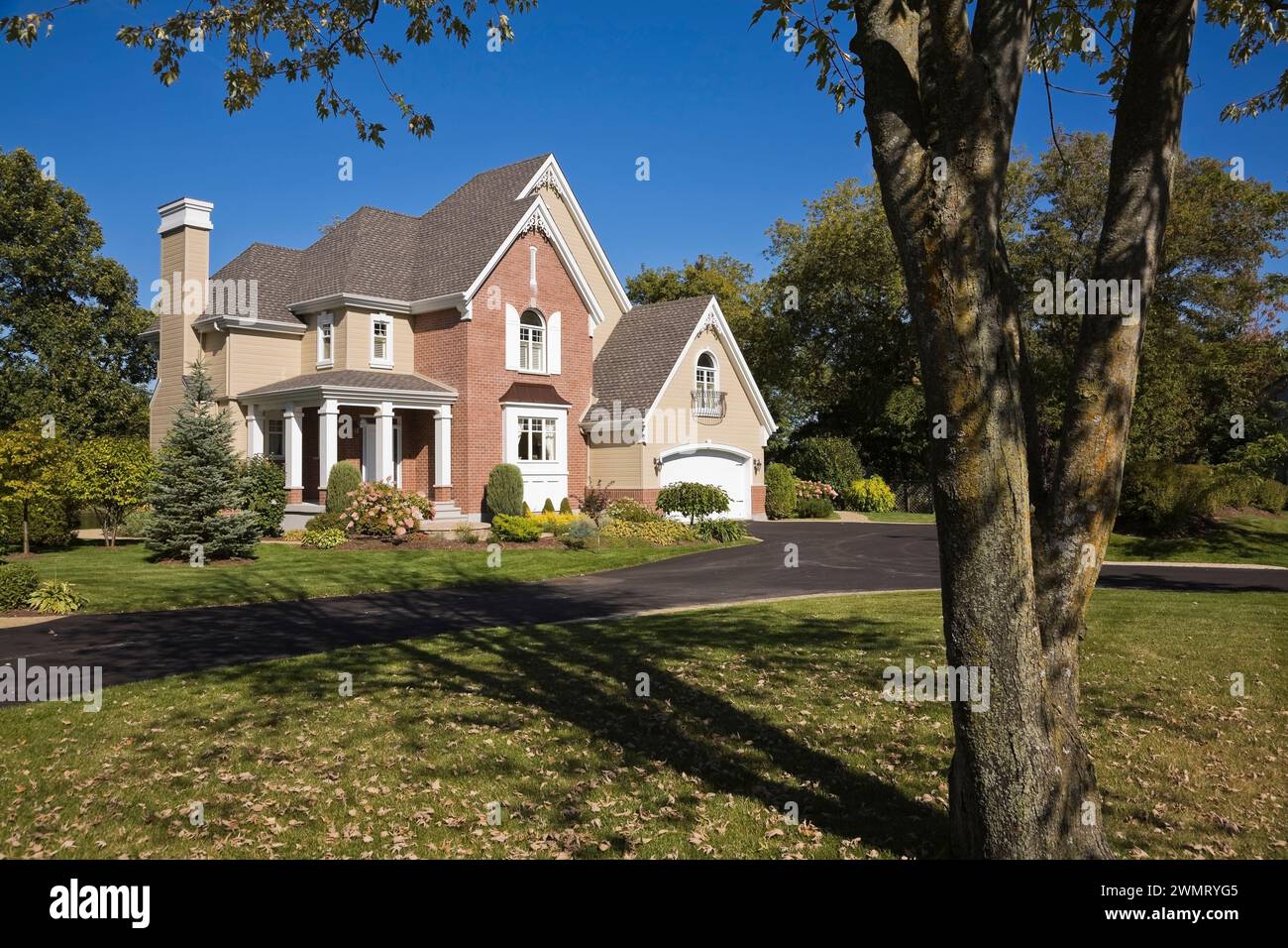 Two story red brick and tan clapboard cladded home with landscaped ...
