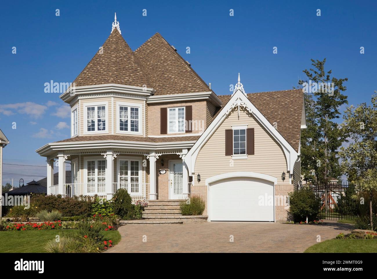 Two story light brown brick and tan clapboard cladded Victorian style ...