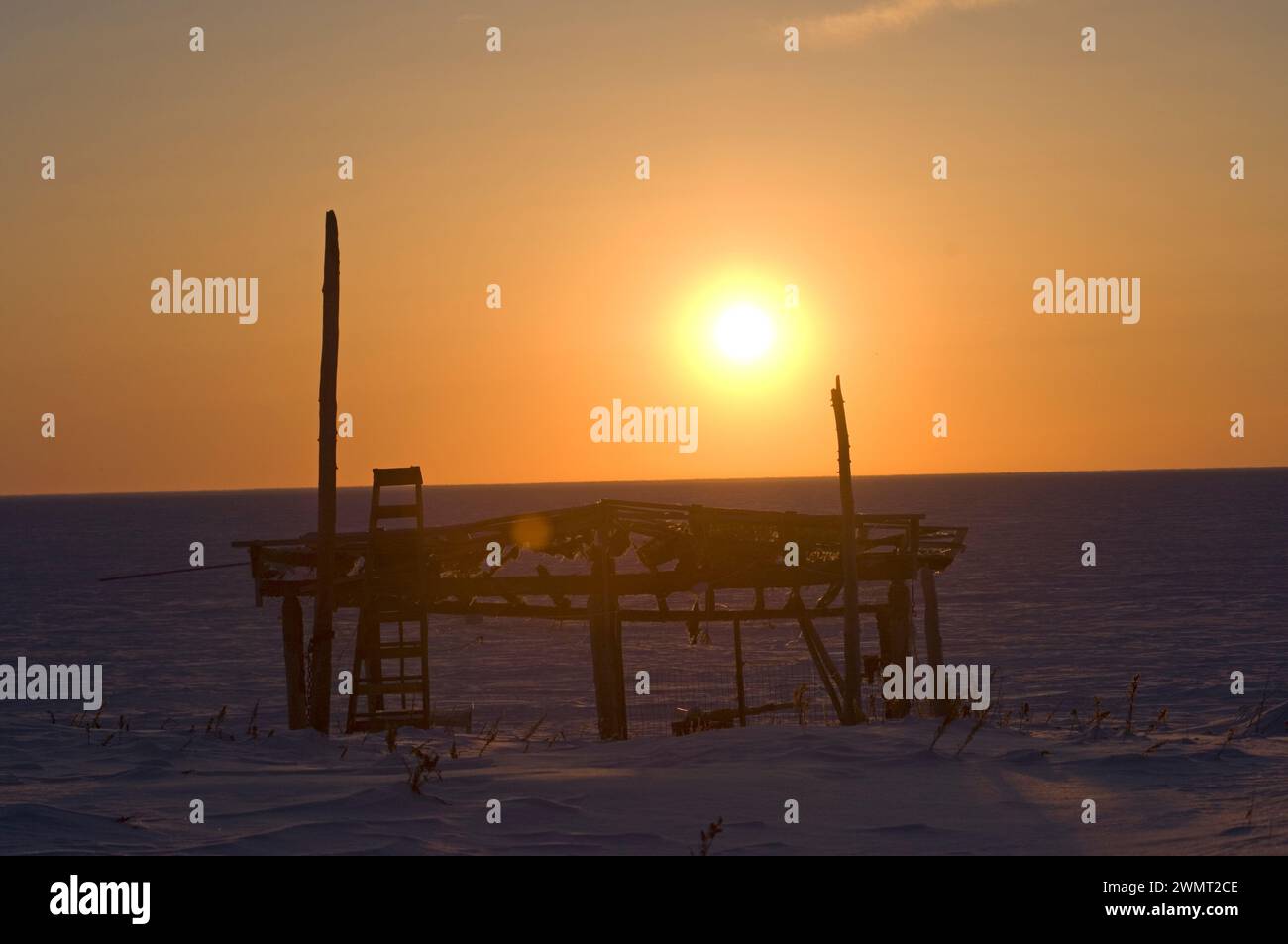 sunset over a wooden storage racks up off the ground for boat umiak ...