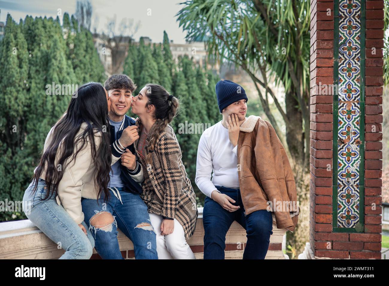 two attractive young girls kissing guy on the face while another guy ...