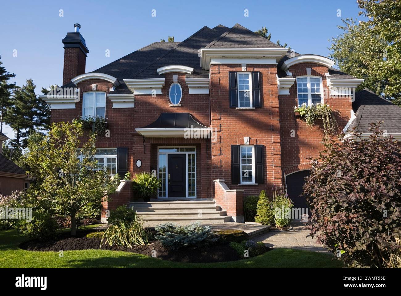 Luxurious two story red brick home with white and black trim and ...