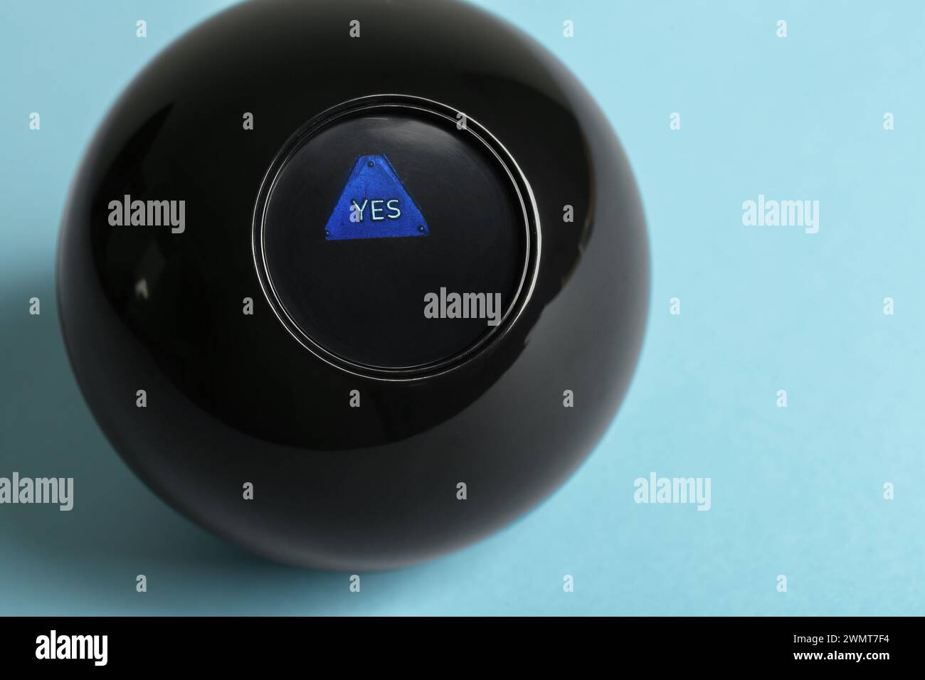 Magic eight ball with prediction Yes on light blue background, closeup ...
