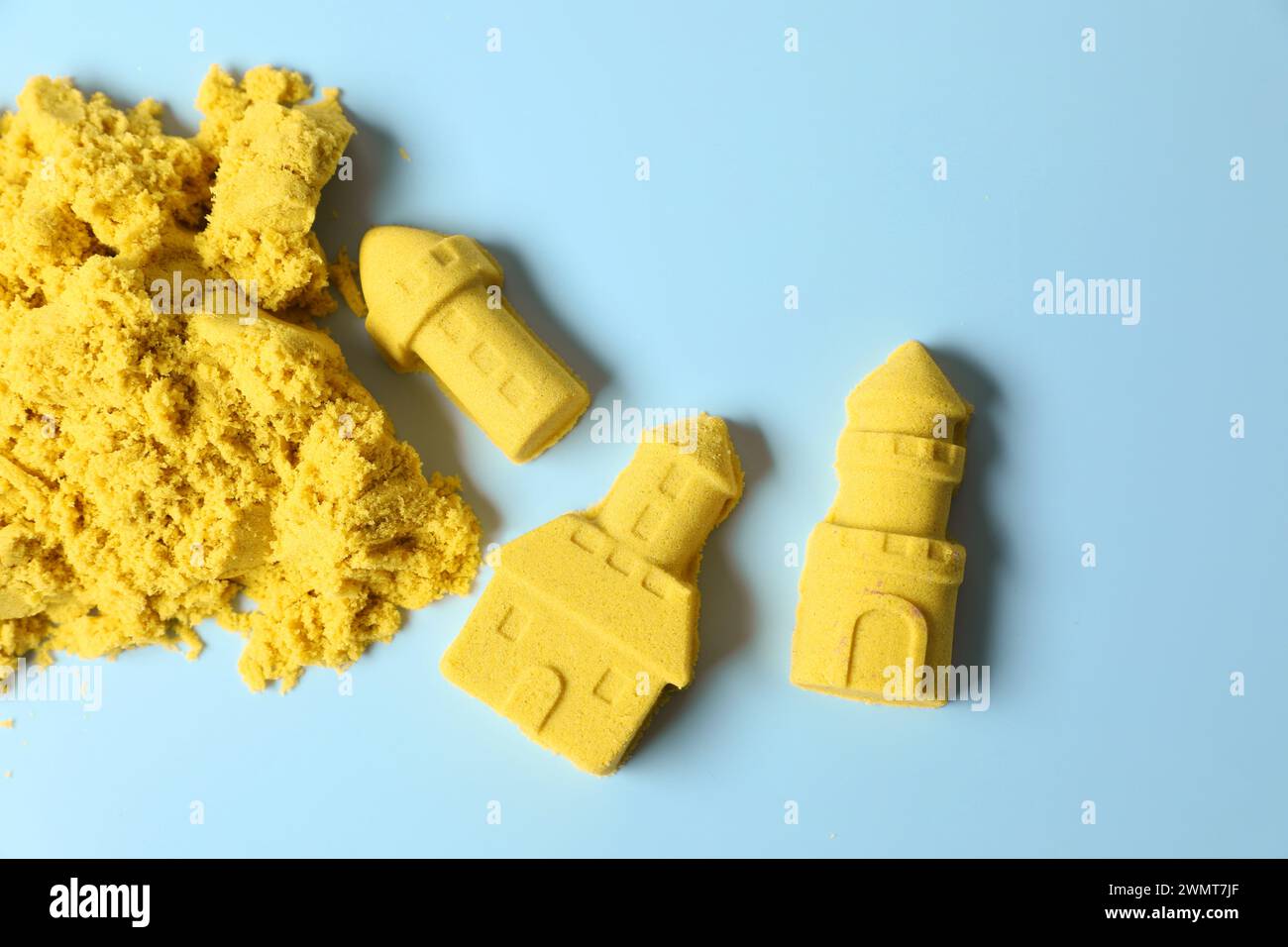 Castle figures made of yellow kinetic sand on light blue background ...