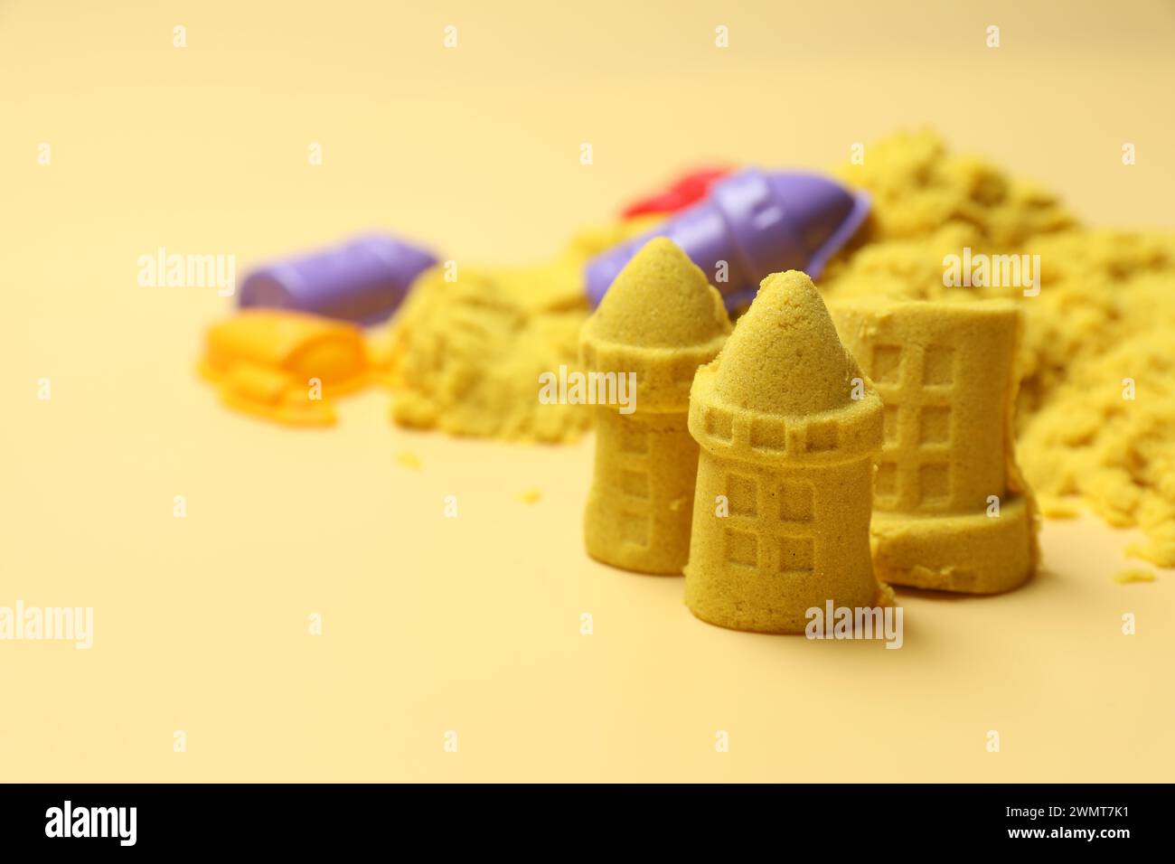 Castle figures made of yellow kinetic sand on beige background, closeup ...