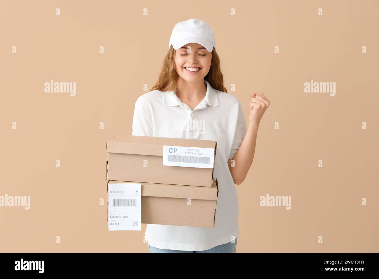 Happy female courier with parcels on beige background Stock Photo - Alamy