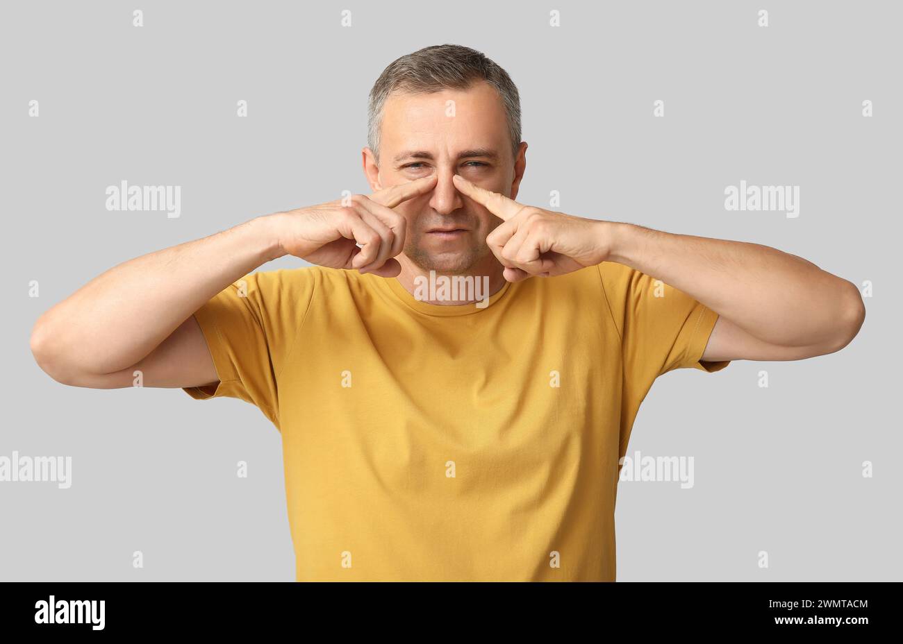 Ill mature man pointing at nose on grey background Stock Photo - Alamy
