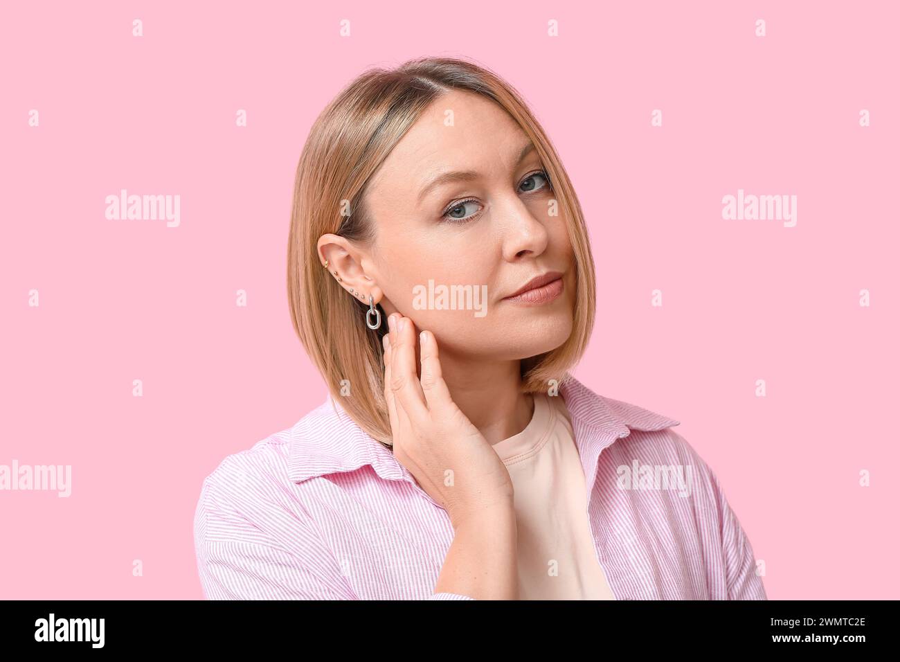 Woman with multiple ear piercing on pink background Stock Photo - Alamy