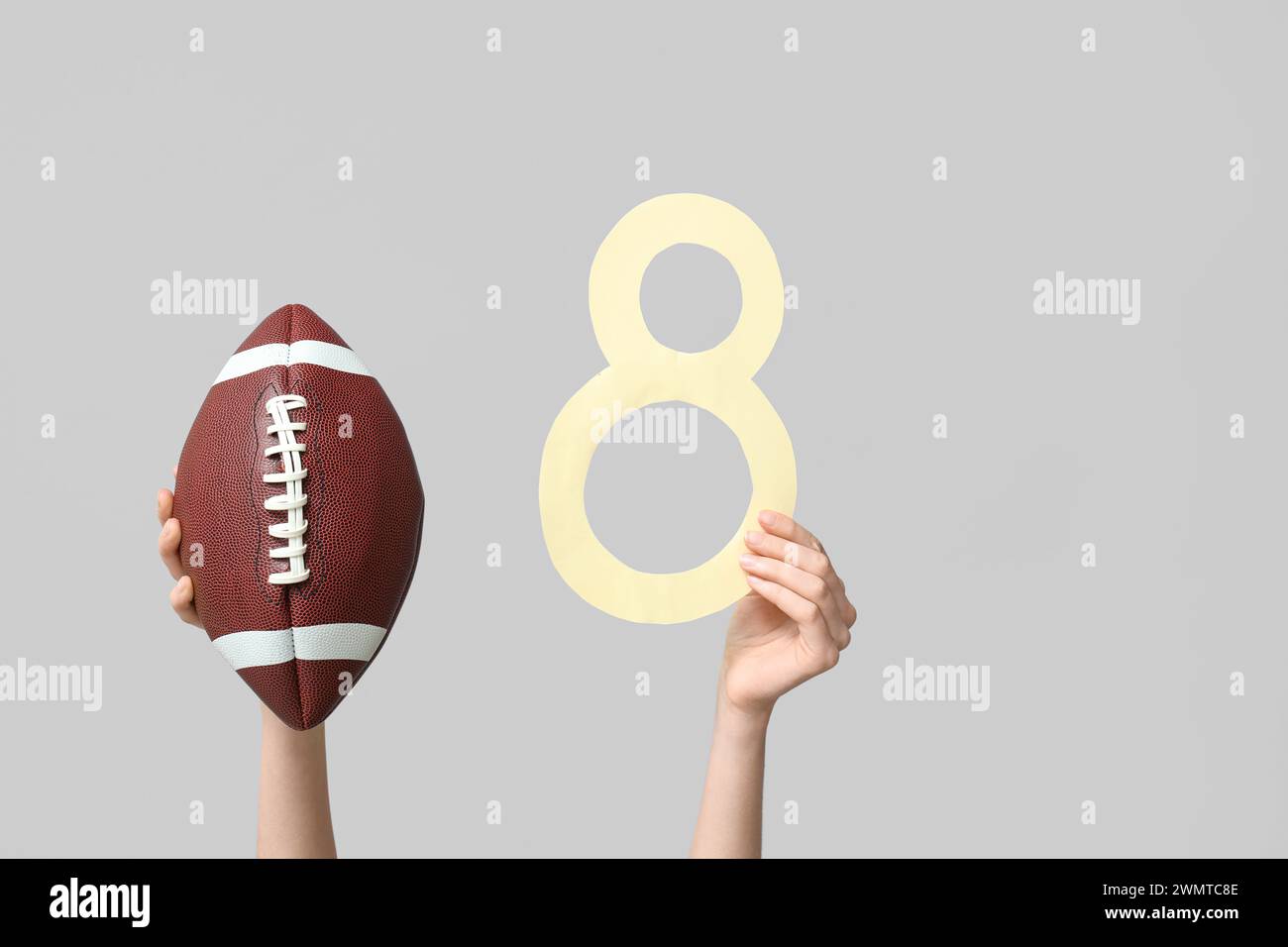 Female hands with paper figure 8 and rugby ball on grey background ...