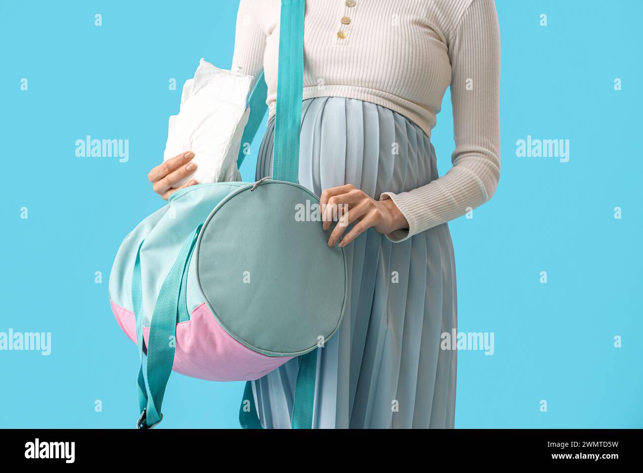 Young pregnant woman with diapers and maternity hospital bag on blue ...