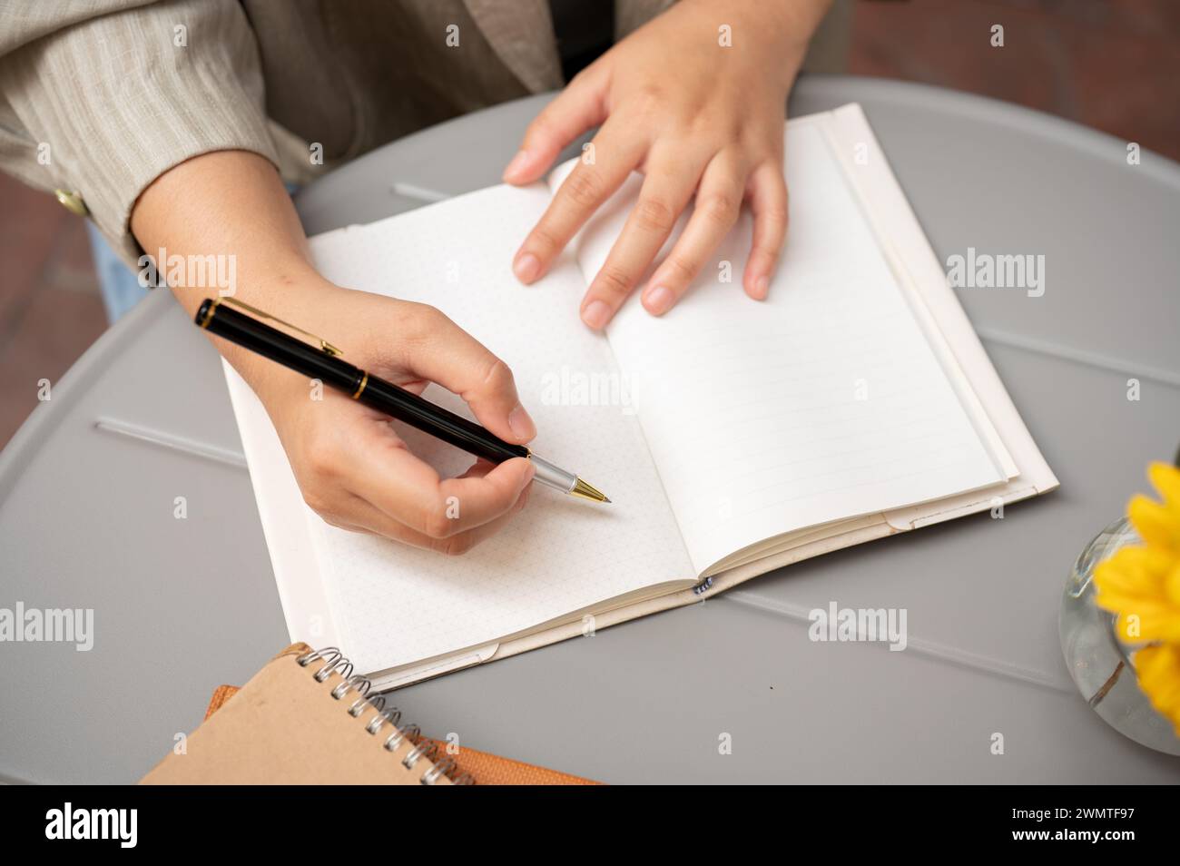 A close-up shot of a businesswoman holding pen, writing something in ...